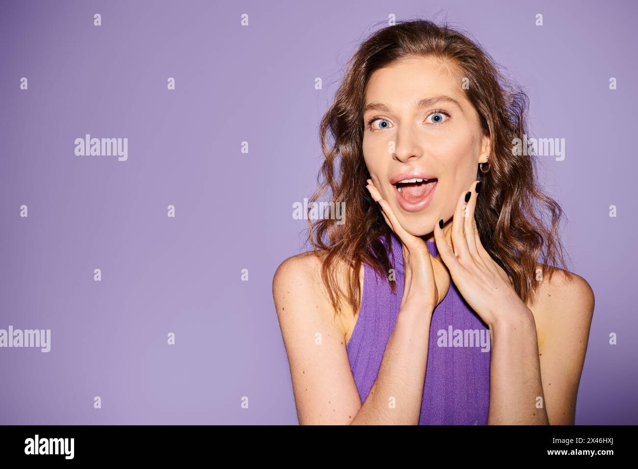 A stylish young woman in a purple top is making a funny face against a ...
