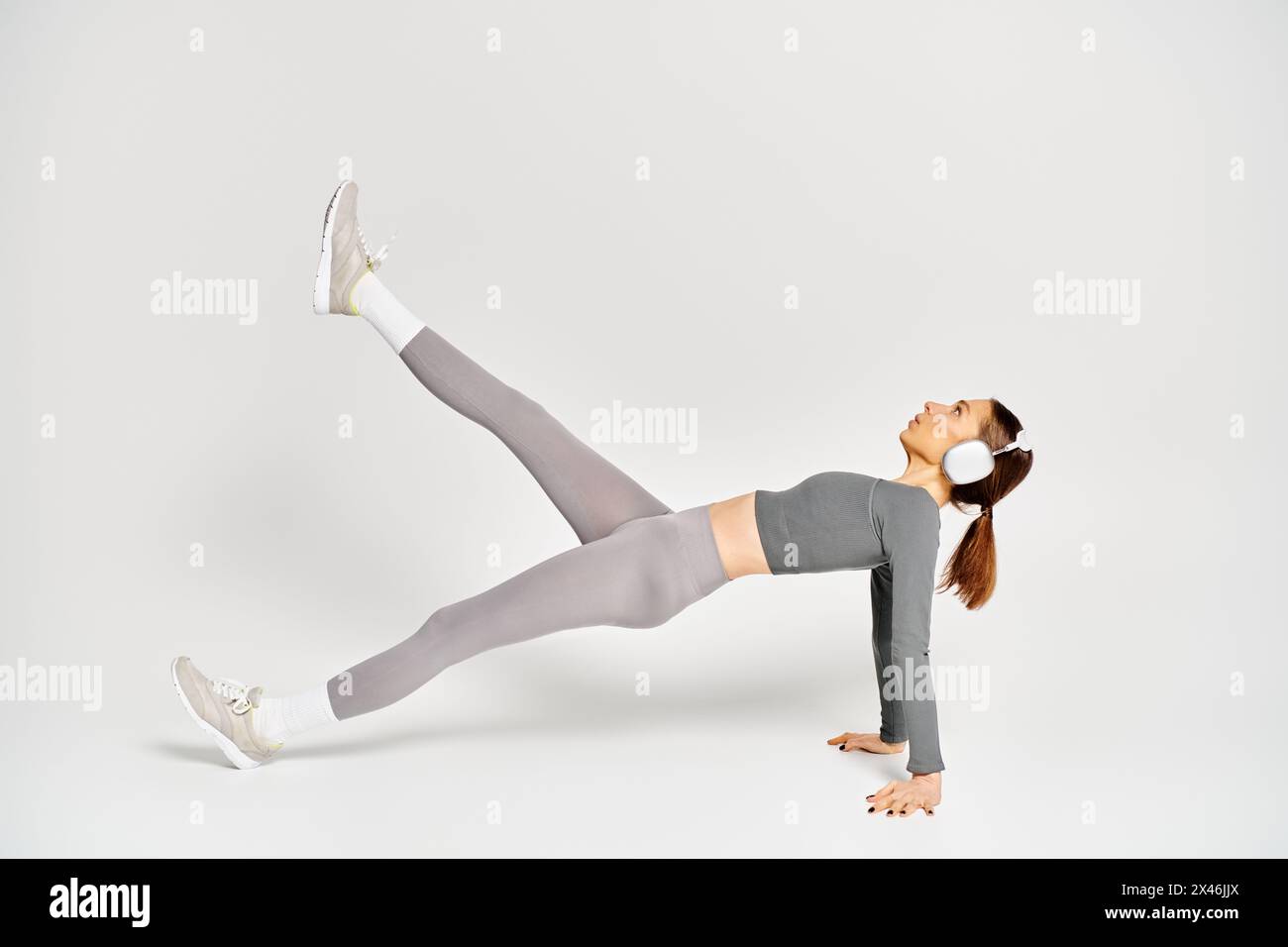 A sporty young woman in activewear demonstrating a side plank exercise ...