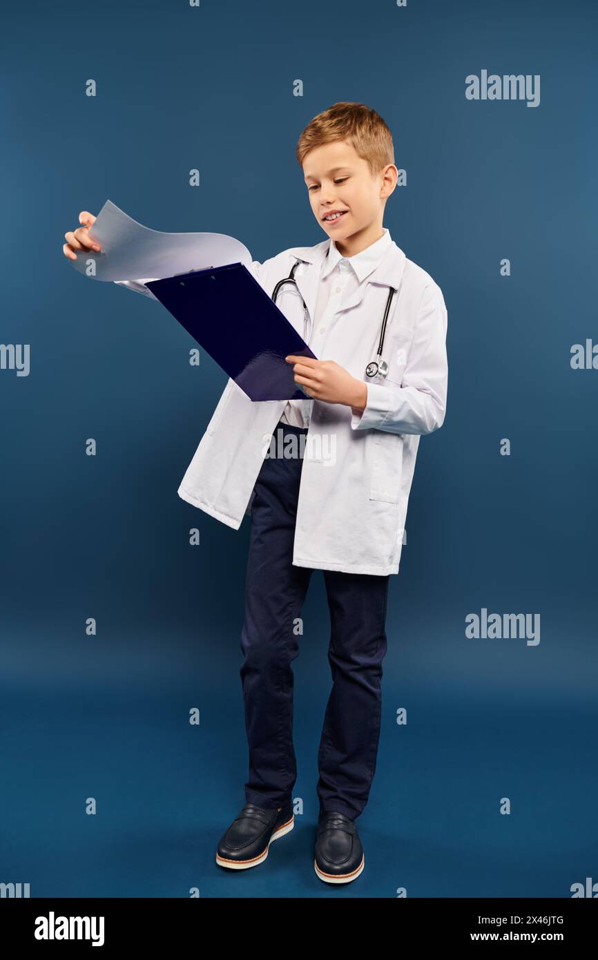 Young boy in lab coat holding clipboard on blue backdrop Stock Photo ...