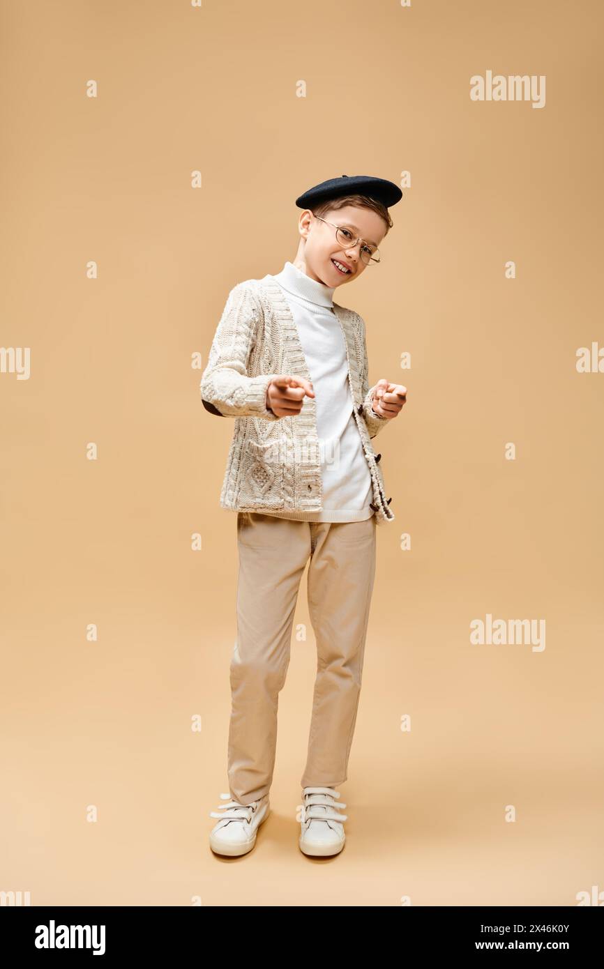 A cute preadolescent boy dressed as a film director on a beige backdrop ...