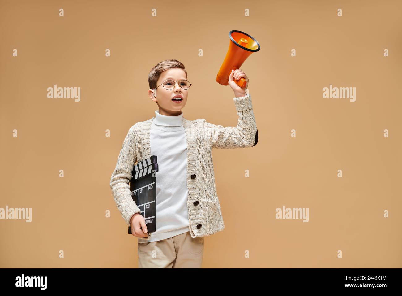 A young boy, dressed as a film director, holds a megaphone and a ...