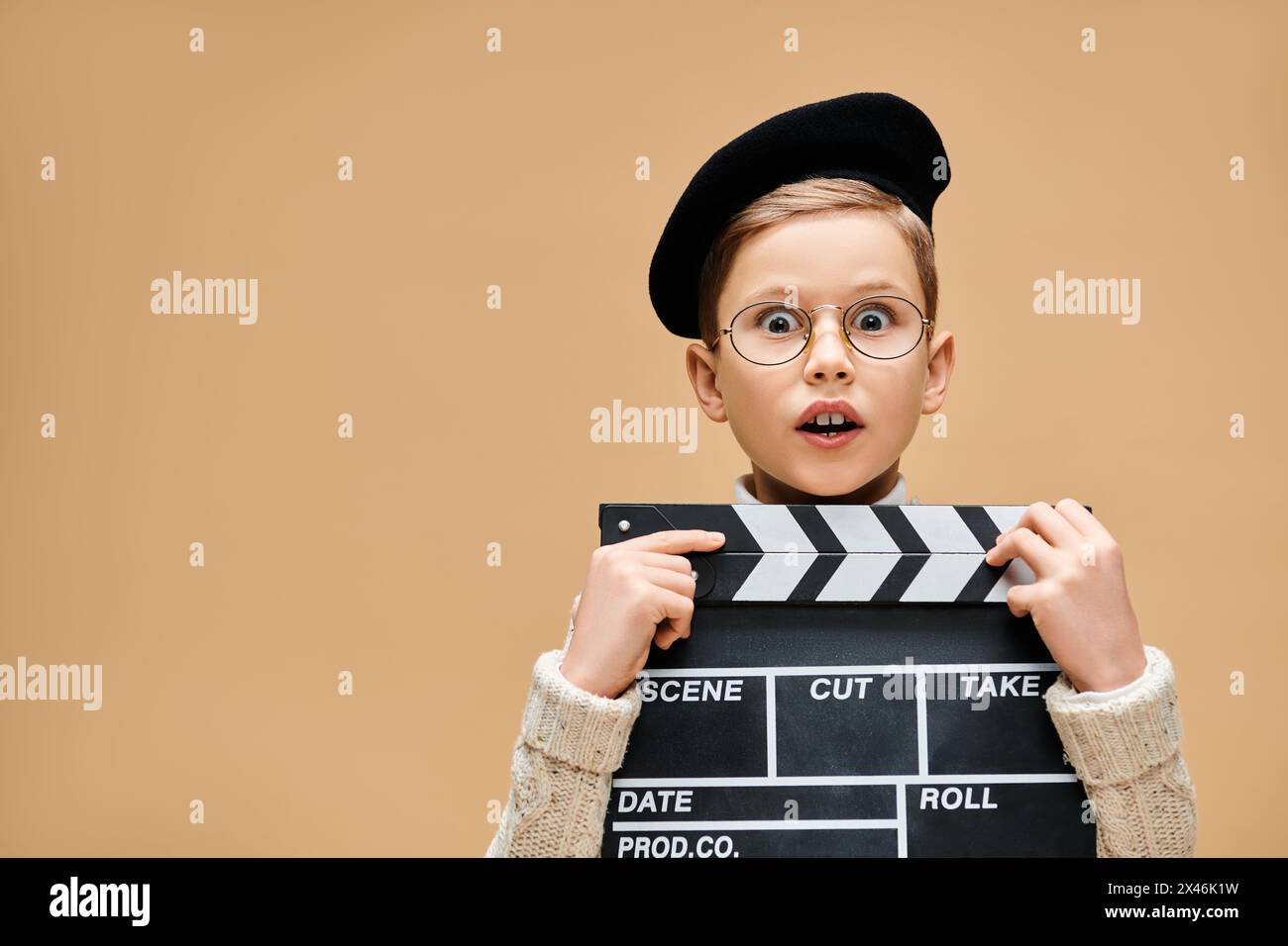 A cute preadolescent boy, dressed as a film director, holds a movie ...