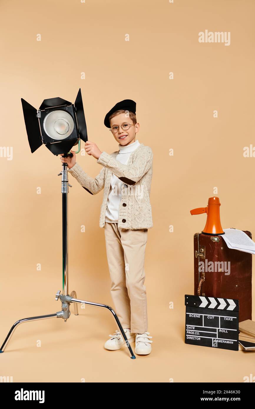 A cute preadolescent boy dressed as a film director poses with a light ...