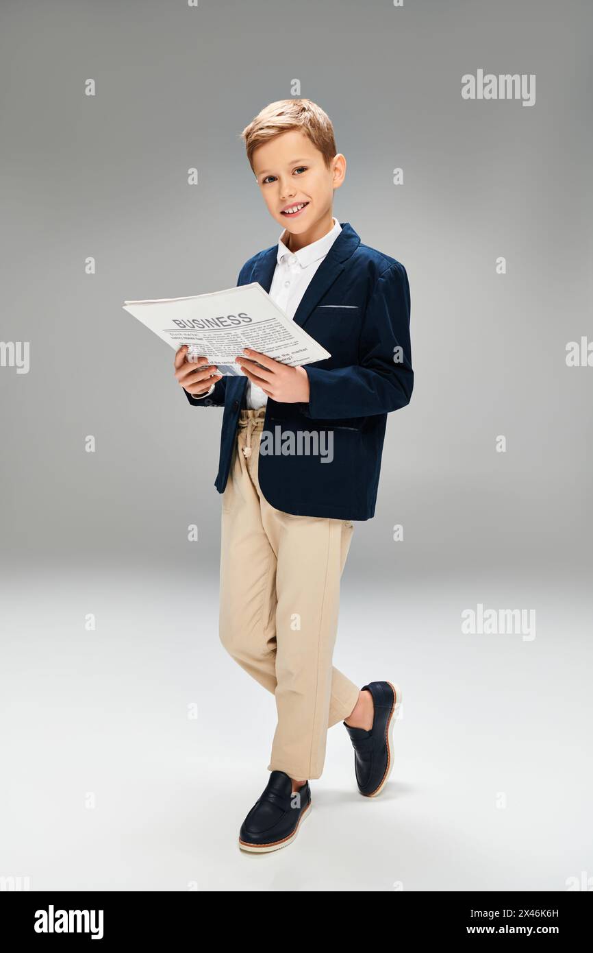 A dapper boy in a blue blazer and khaki pants engrossed in reading ...
