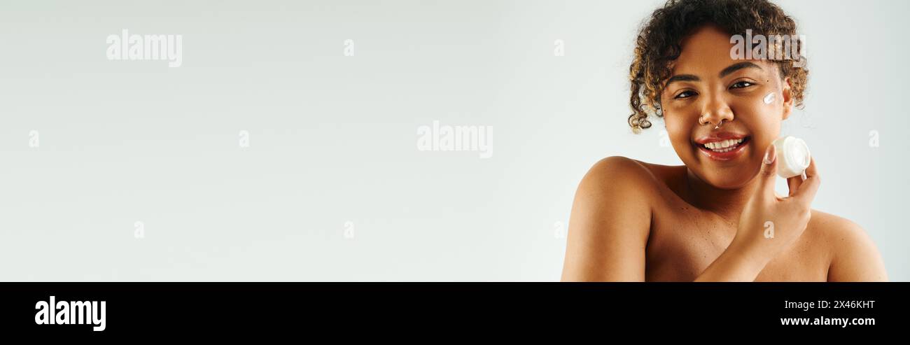 Alluring African American woman applying cream to her face Stock Photo ...