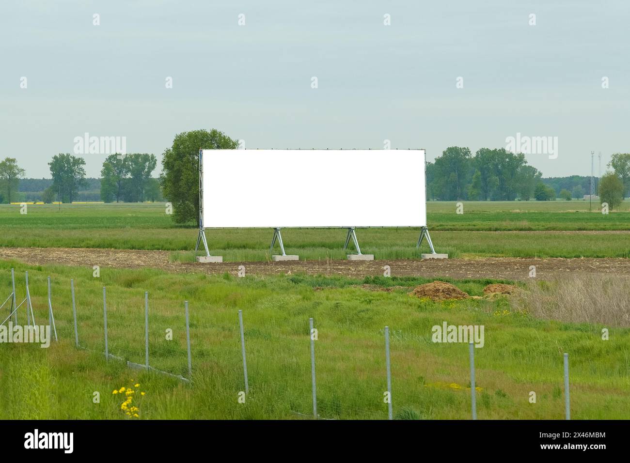 A massive billboard stands in the middle of a field, enclosed by a ...