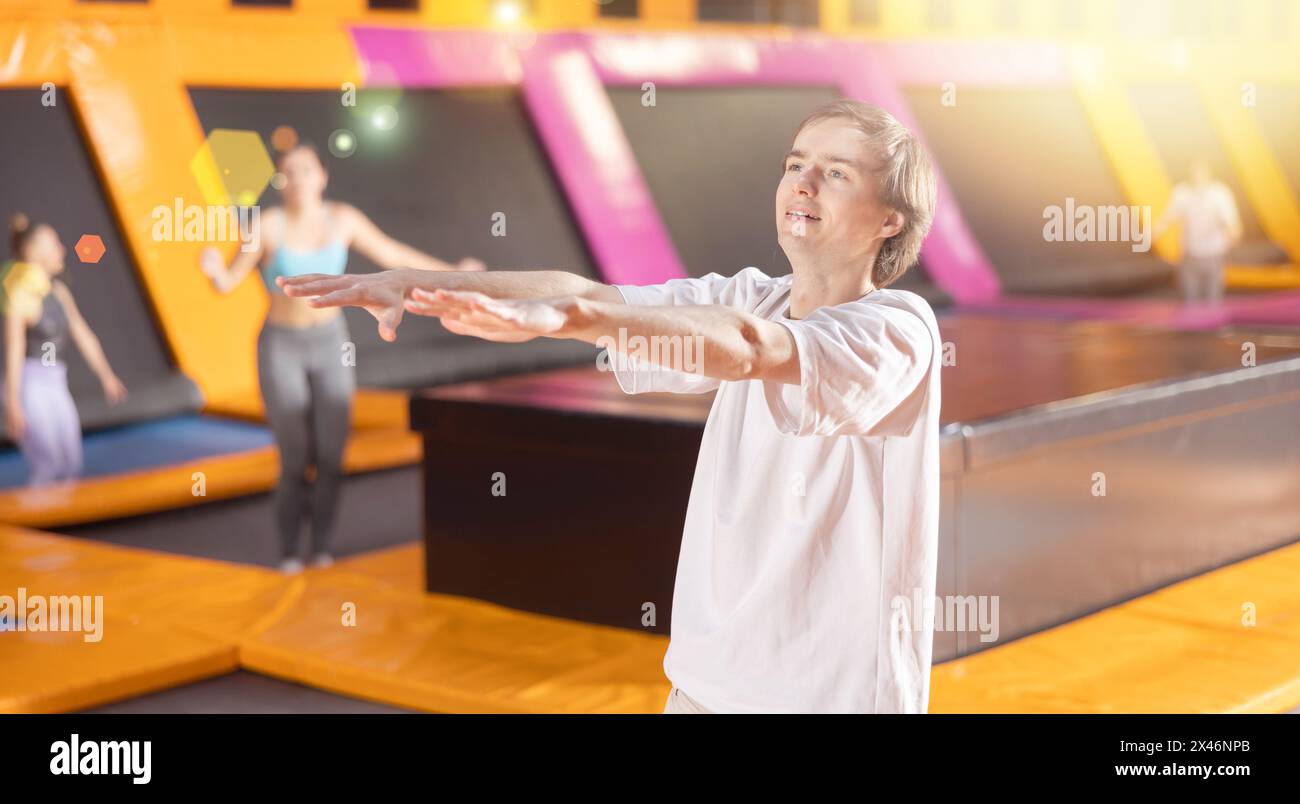 Portrait of positive young man posing on trampolines during active ...