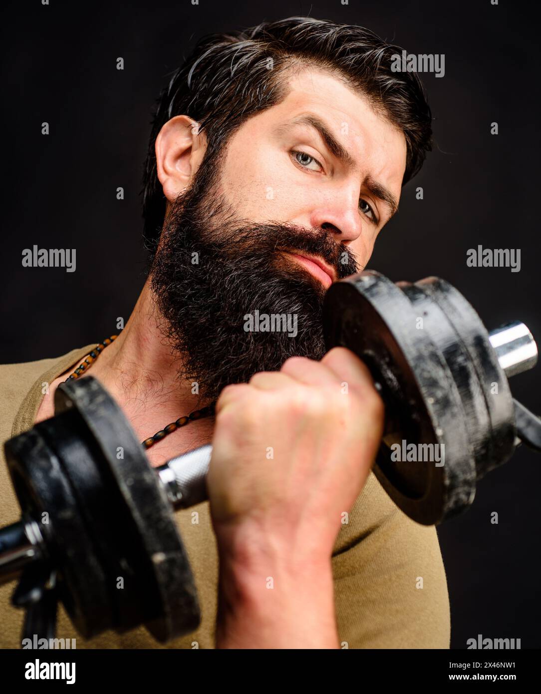 Strong bearded muscular sportsman lifting dumbbell. Closeup portrait. Sporty bodybuilder pumping ...