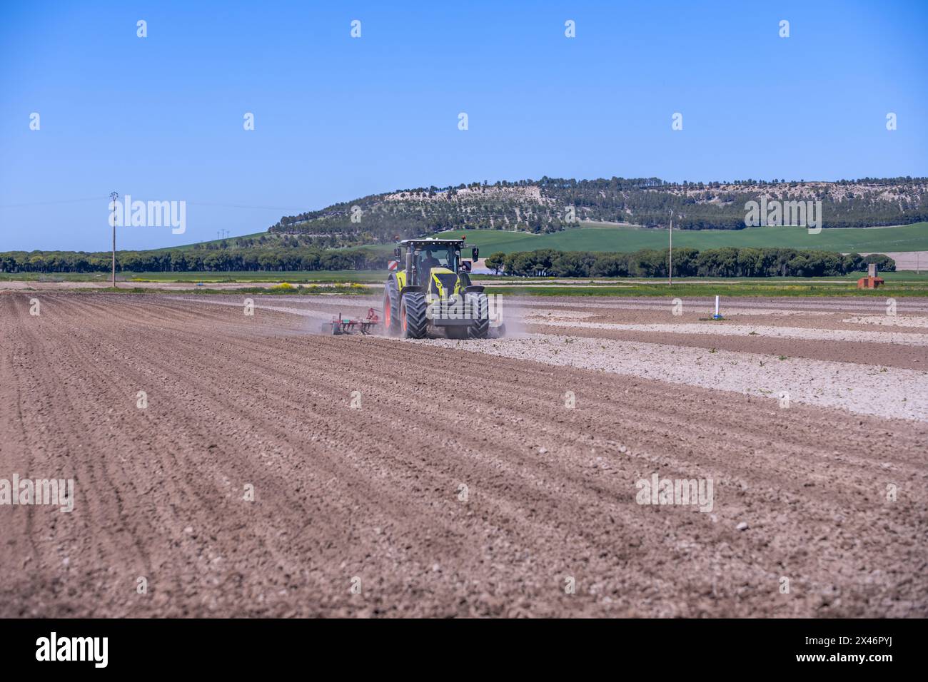 A green tractor pulling a red plow through a crop field Stock Photo - Alamy