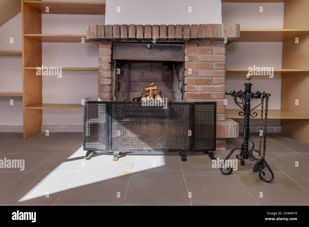 Fireplace of a house with security grill on a wall with wooden shelves ...