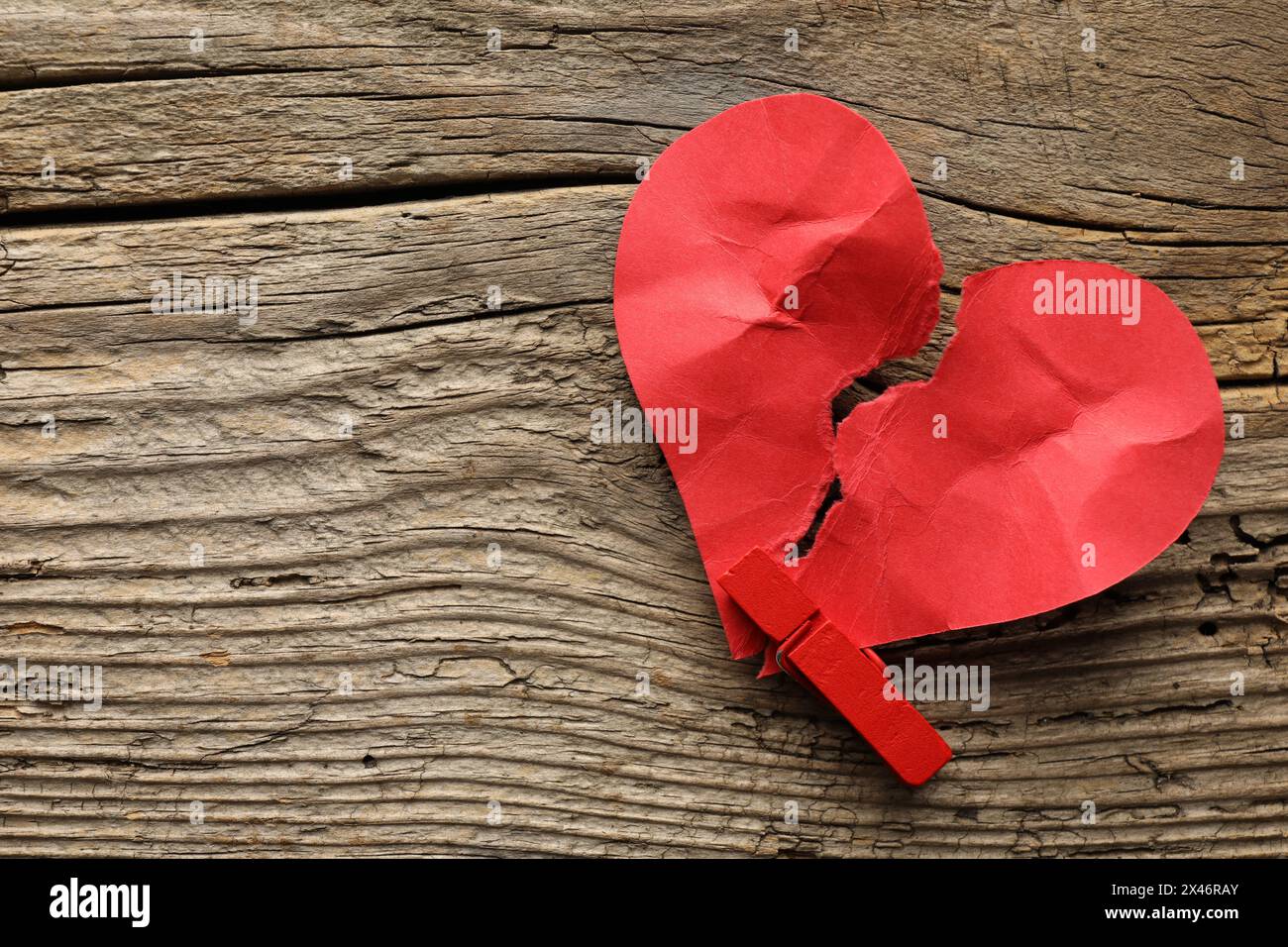 Broken heart. Torn red paper heart with clothespin on wooden table, top ...