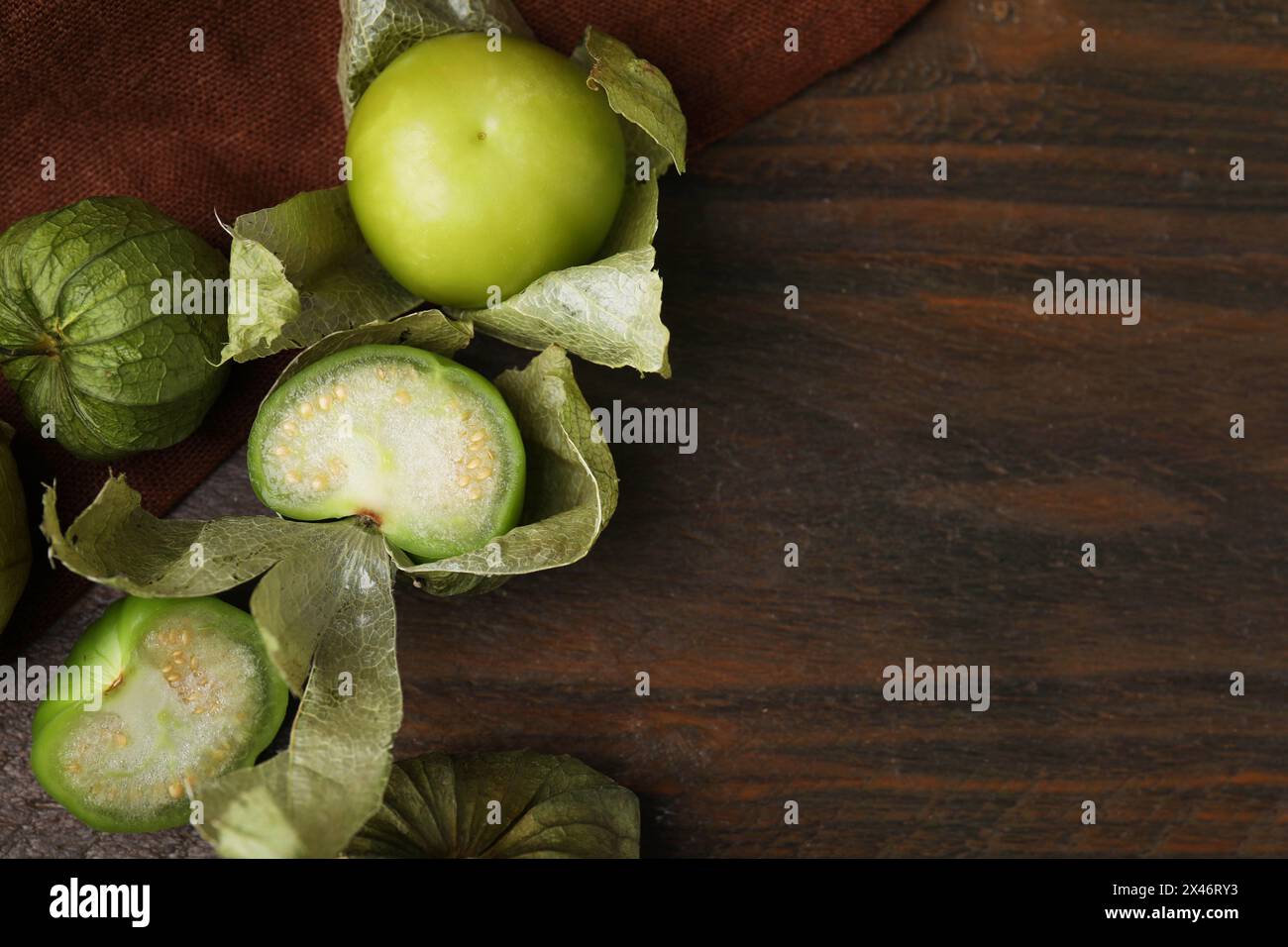 Fresh green tomatillos with husk on wooden table, flat lay. Space for ...