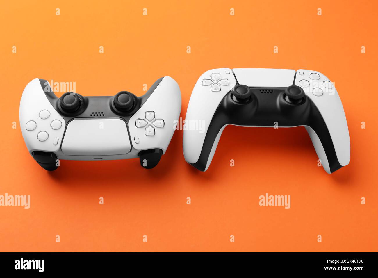 Two wireless game controllers on orange background Stock Photo - Alamy