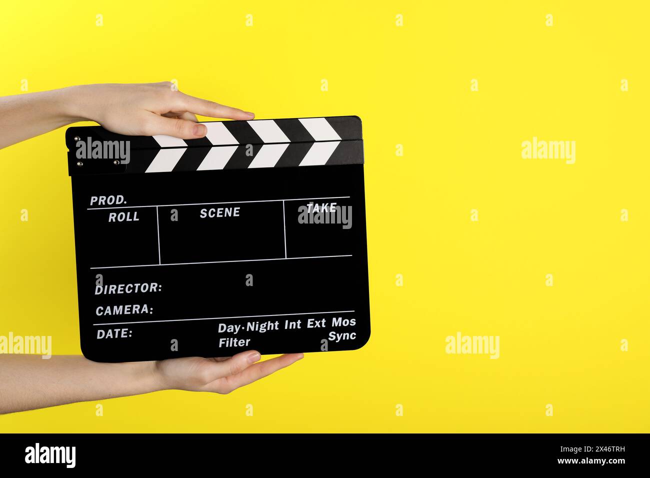 Woman holding movie clapper on yellow background, closeup. Space for ...
