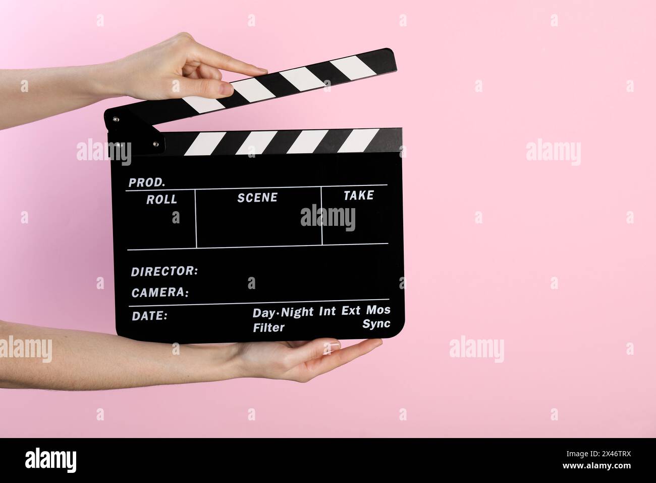 Woman holding movie clapper on pink background, closeup. Space for text ...