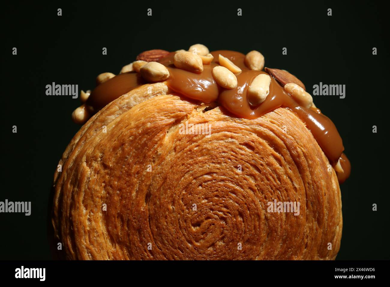 Round croissant with chocolate paste and nuts on black background ...