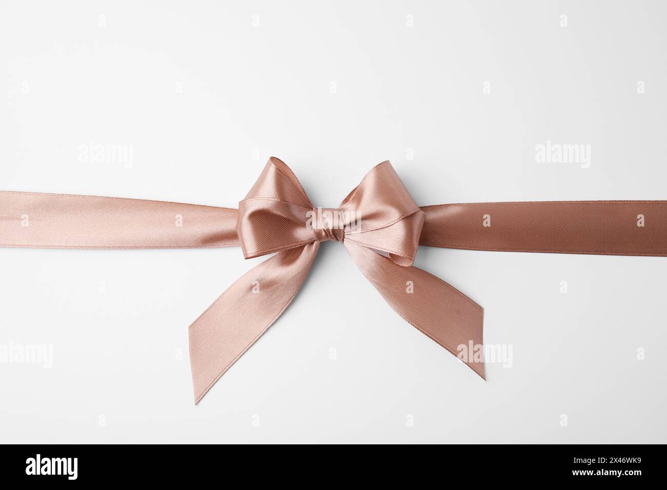 Beige satin ribbon with bow on white background, top view Stock Photo ...