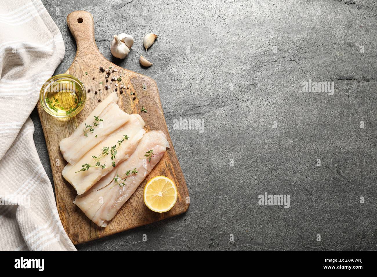 Raw cod fish, microgreens, oil, spices and lemon on grey textured table ...