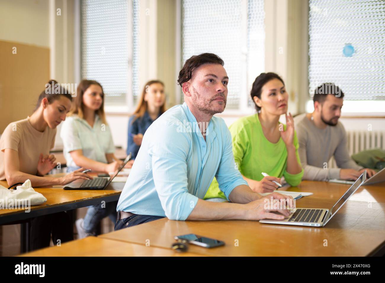 Handsome male student typing on laptop during lecture at university ...