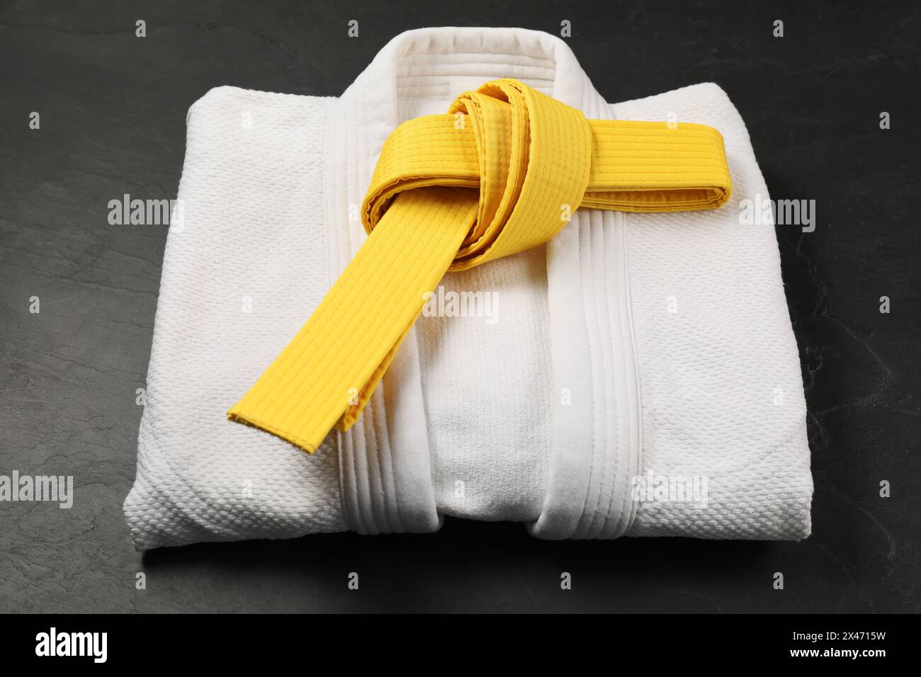 Yellow karate belt and white kimono on gray background Stock Photo - Alamy
