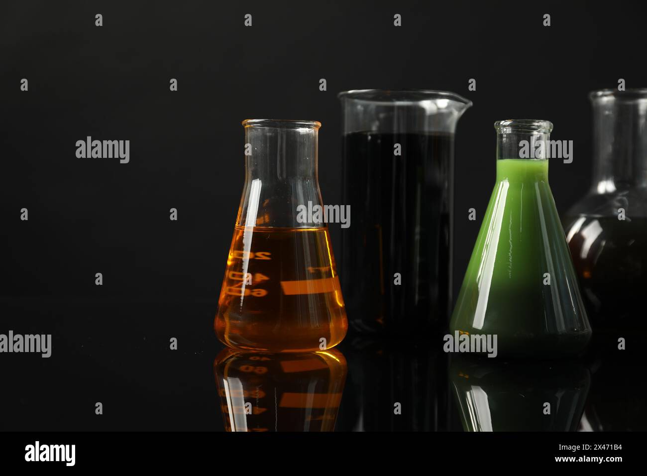 Glass flasks and beaker with different types of oil on black background ...