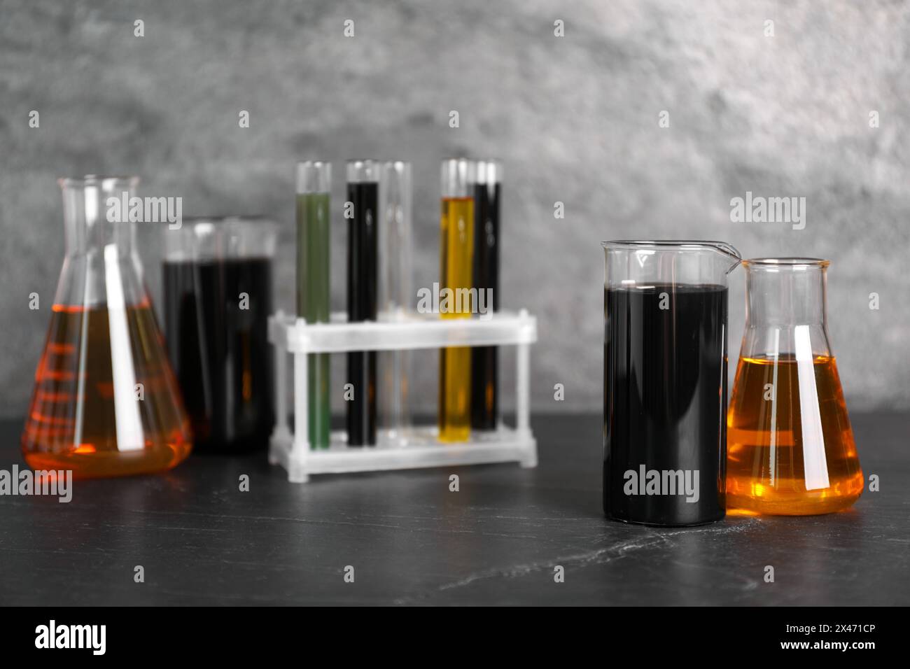Beakers, flasks and test tubes with different types of oil on grey ...