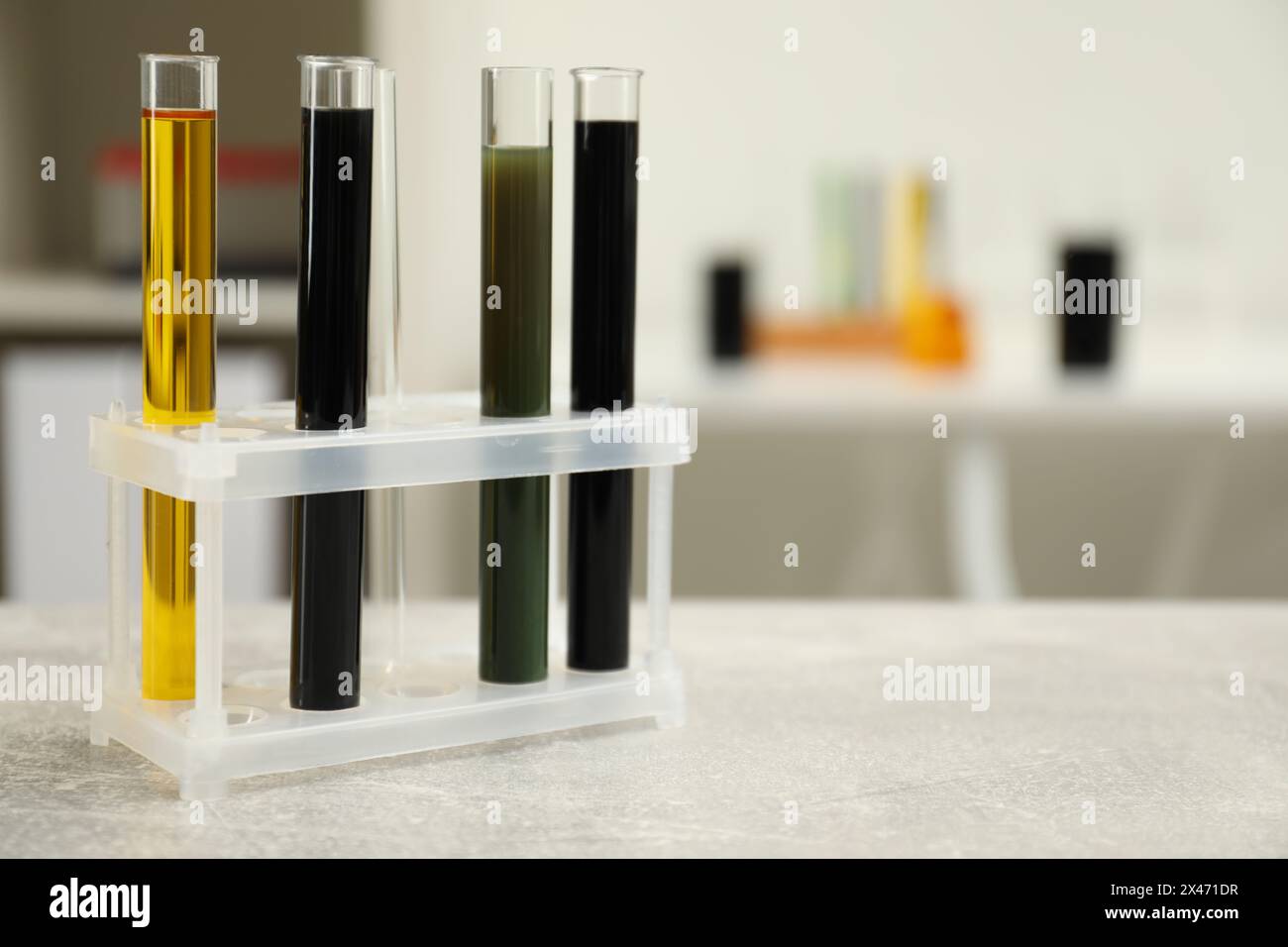 Test tubes with different types of crude oil on light grey table, space ...