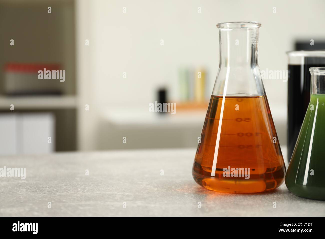 Flasks and beaker with different types of crude oil on light grey table ...