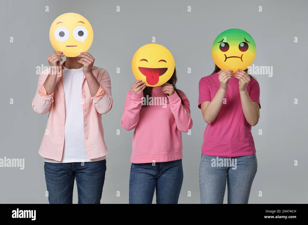 People covering faces with emoticons on grey background Stock Photo - Alamy