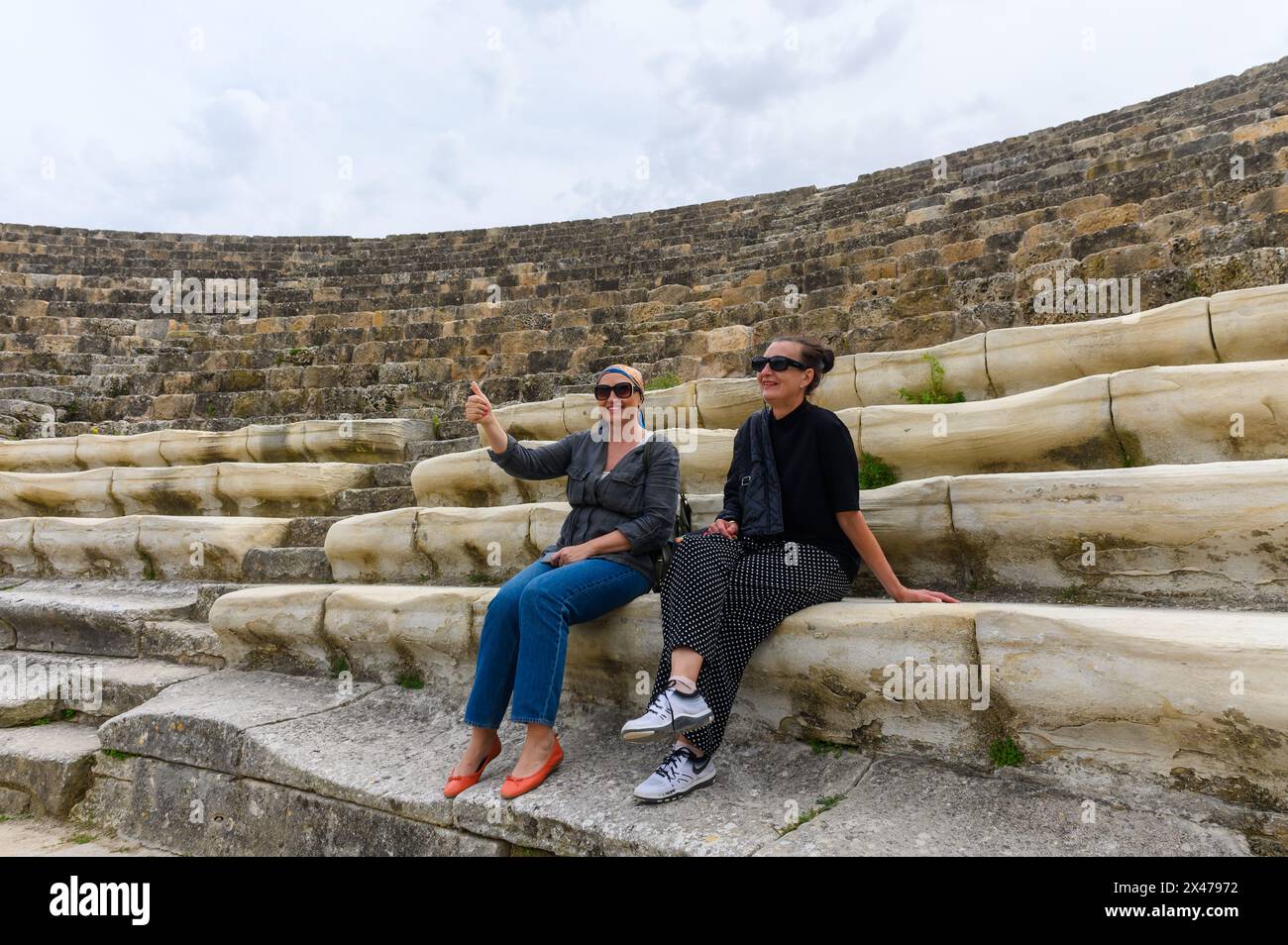 2 women sitting in an amphitheater in an ancient ruined city ...