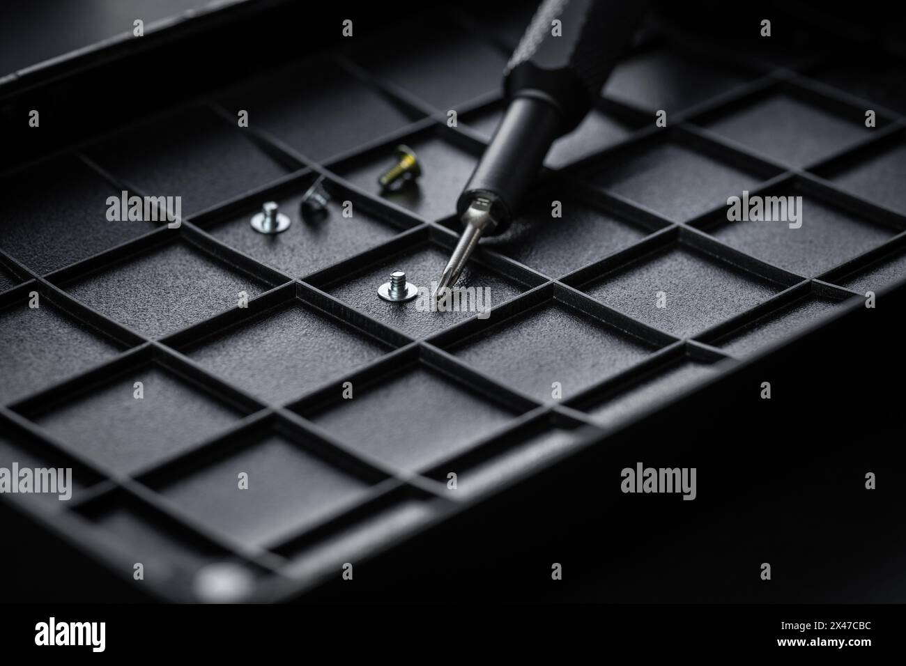 Torx drive bit and aluminum bit driver on black sorting tray. Screws ...