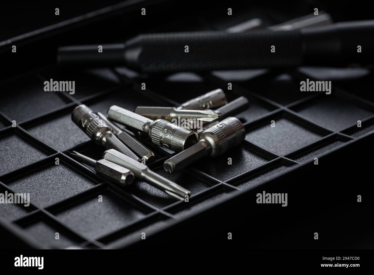 Torx drive bit and aluminum bit driver on black sorting tray. Screws ...