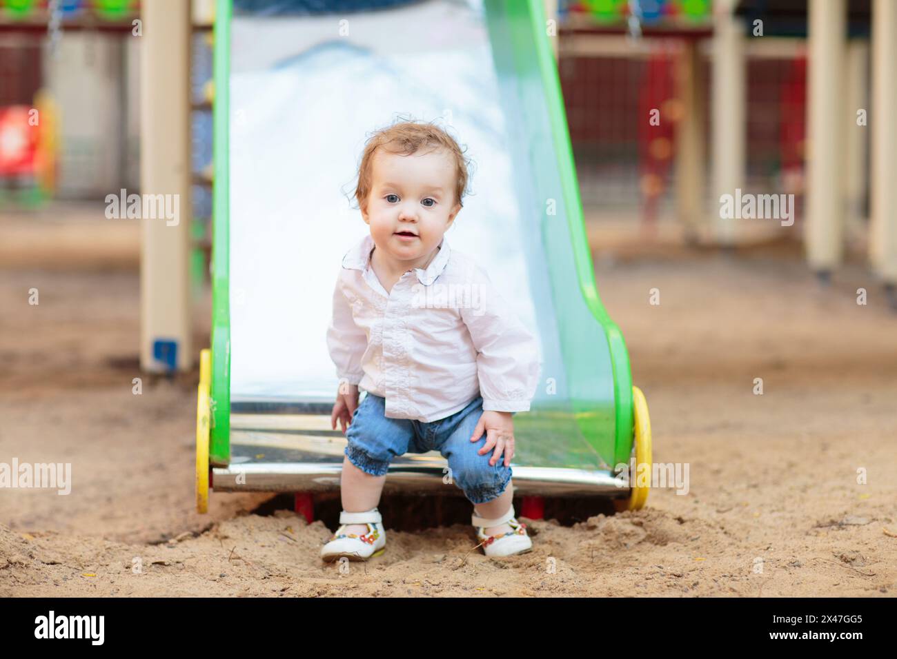 Child playing on playground on sunny summer day in a park. Kids swing ...