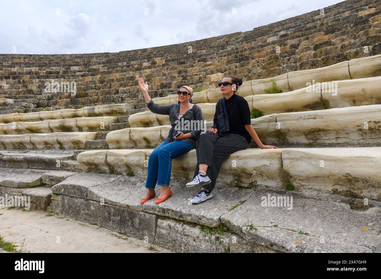 2 women sitting in an amphitheater in an ancient ruined city ...