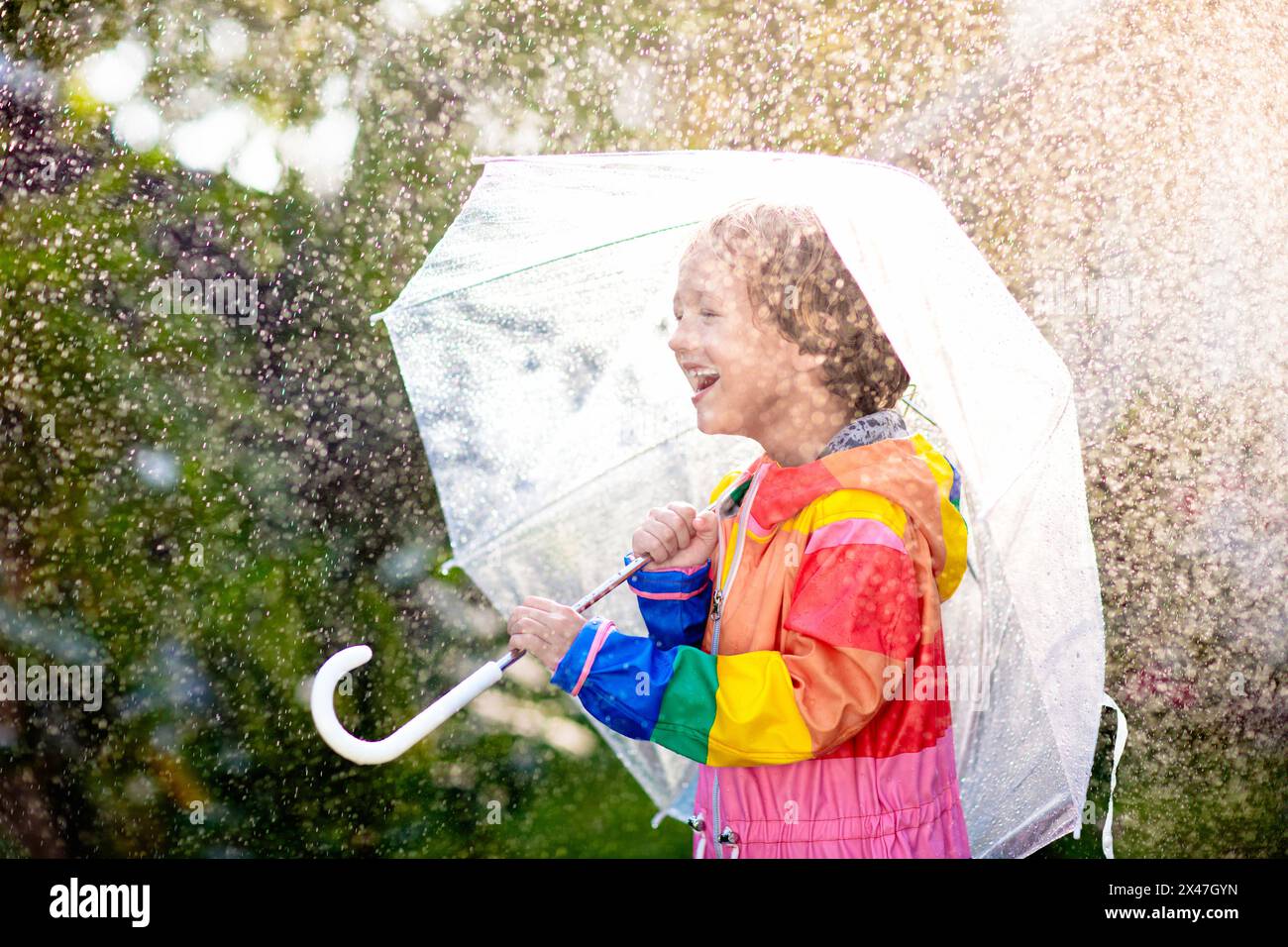 Child playing in autumn rain. Kid with umbrella. Little boy running in ...