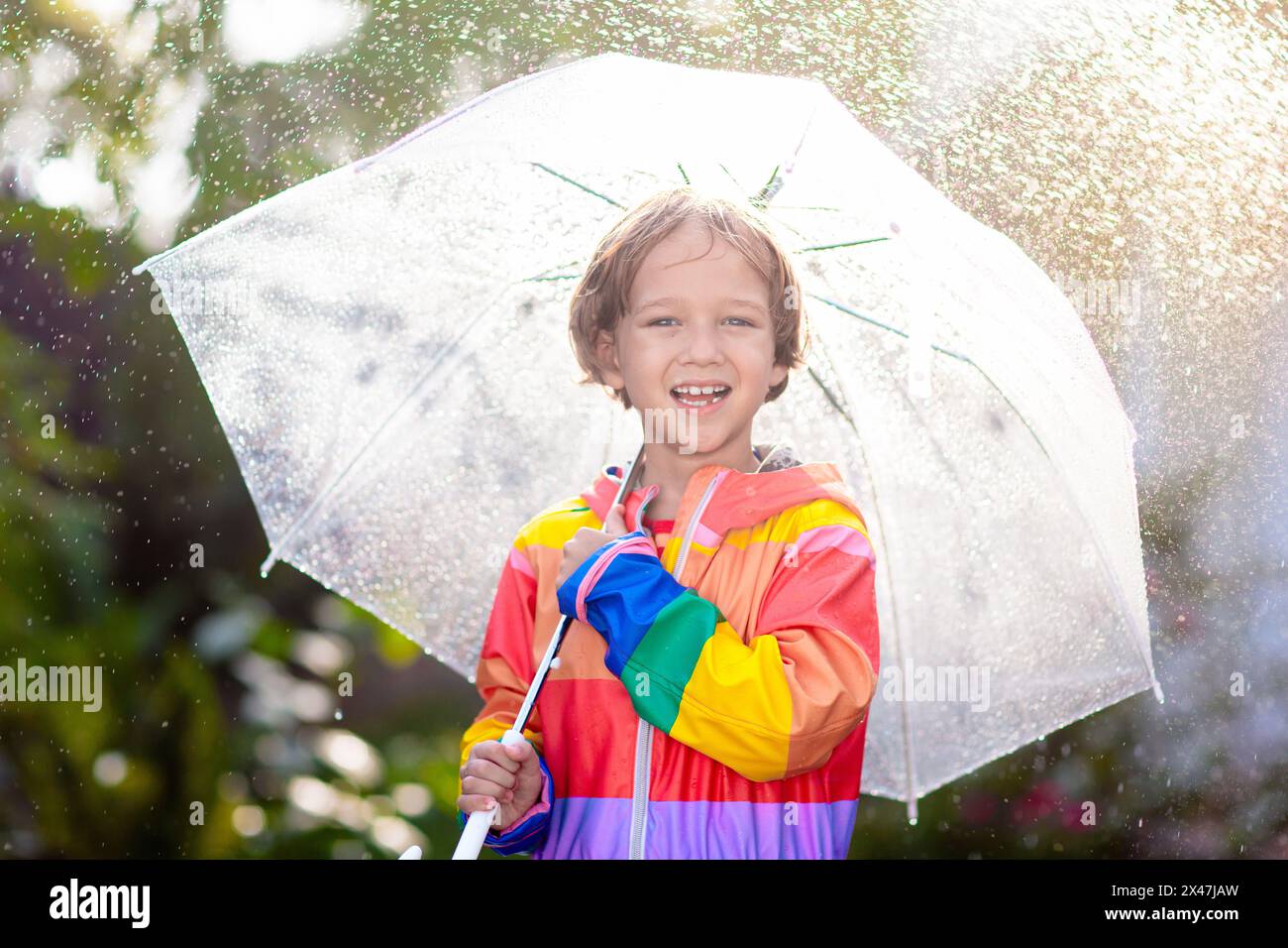 Child playing in autumn rain. Kid with umbrella. Little boy running in ...