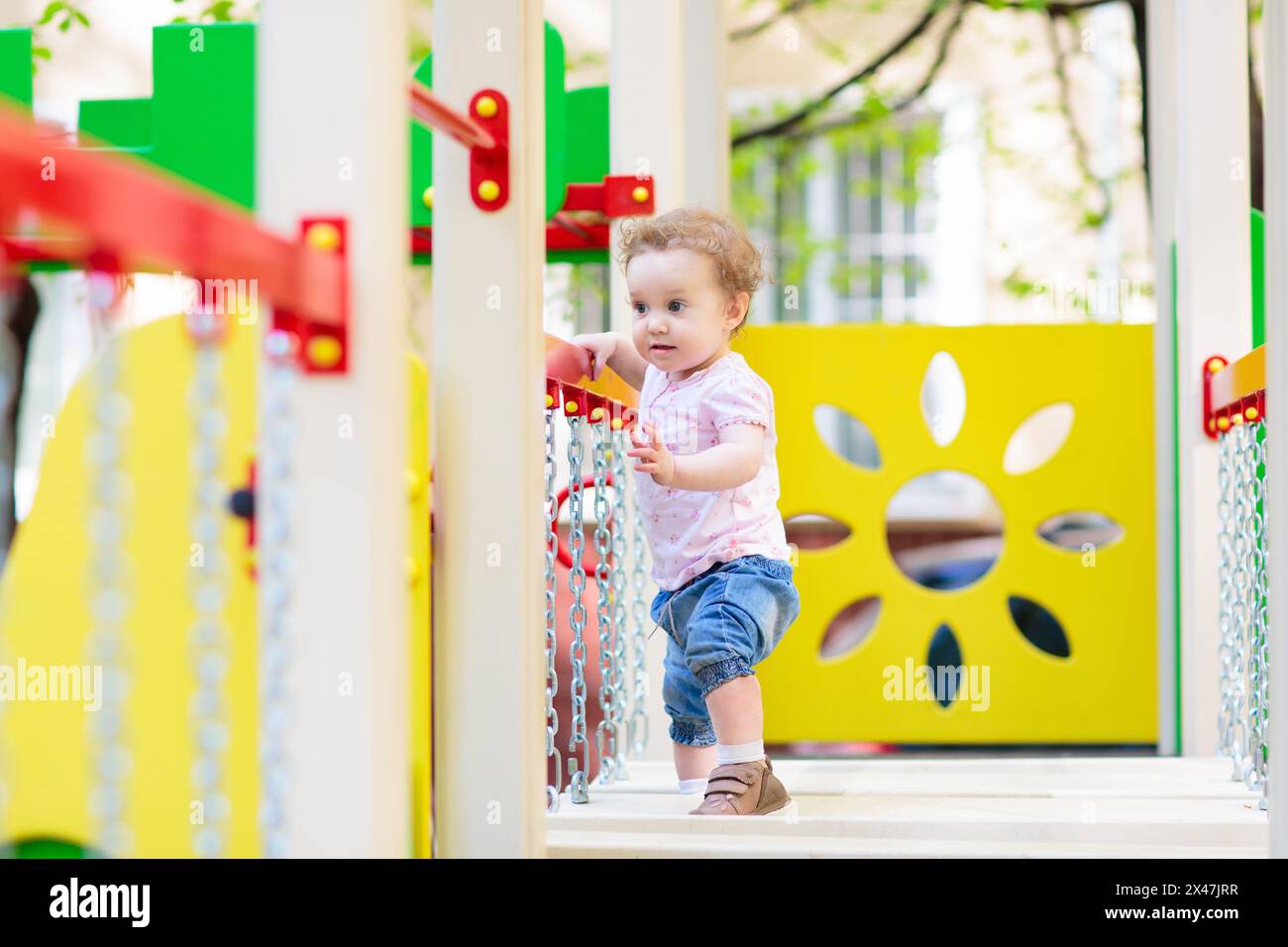 Child playing on playground on sunny summer day in a park. Kids swing ...