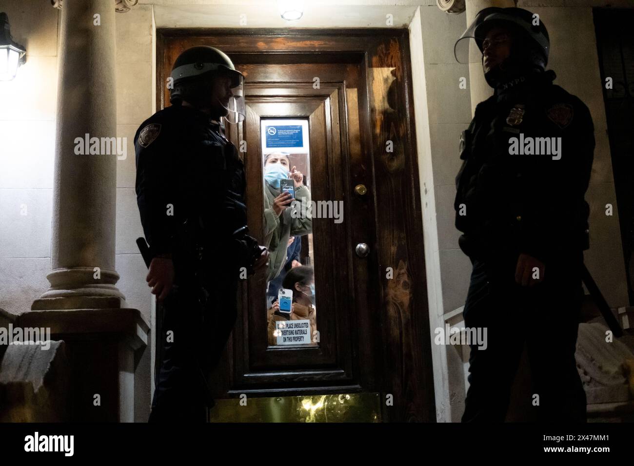 A students watch through their building door, NYPD stands guard ...