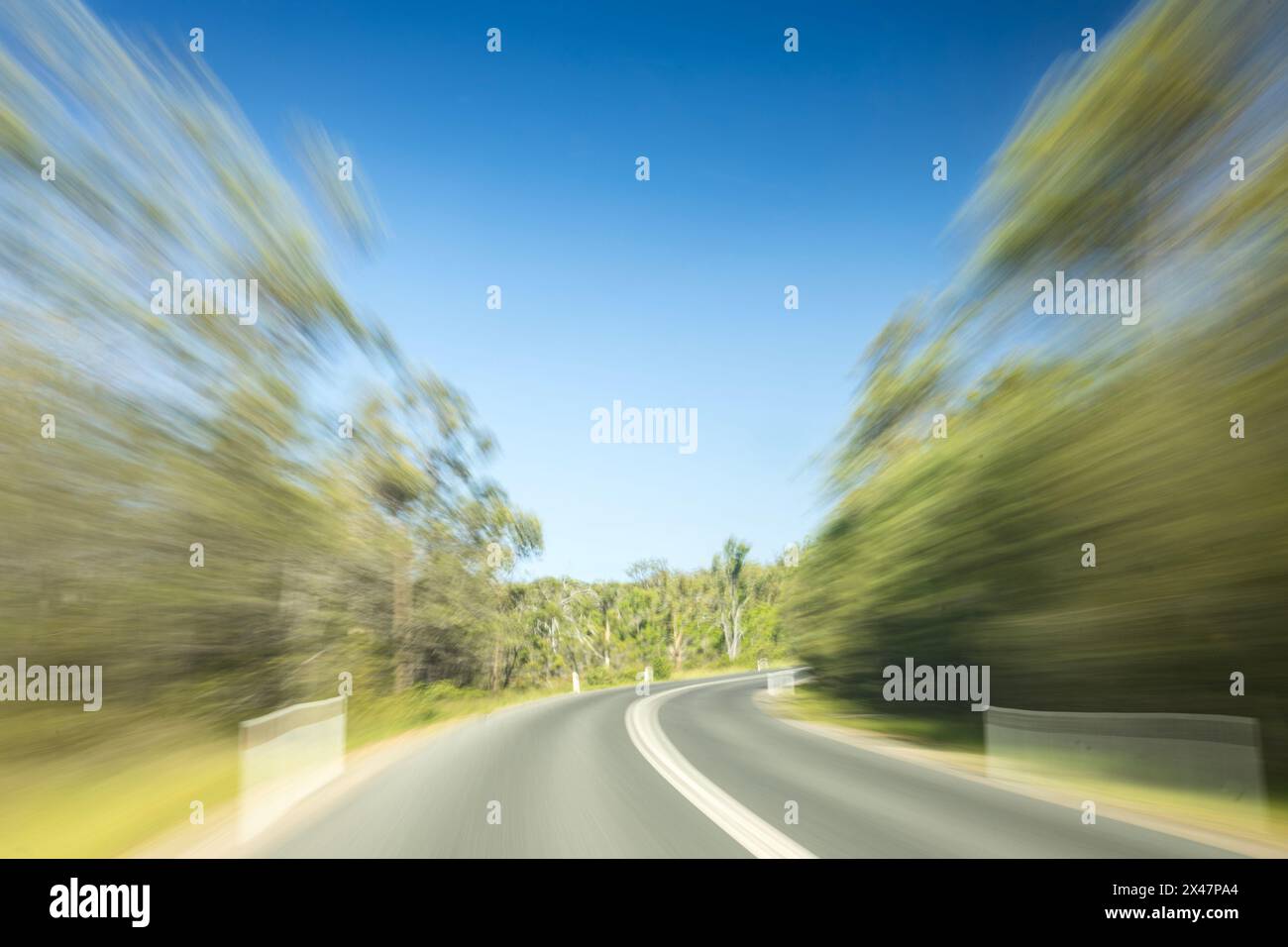 long exposure photo of car driving on road with blurred trees passing ...