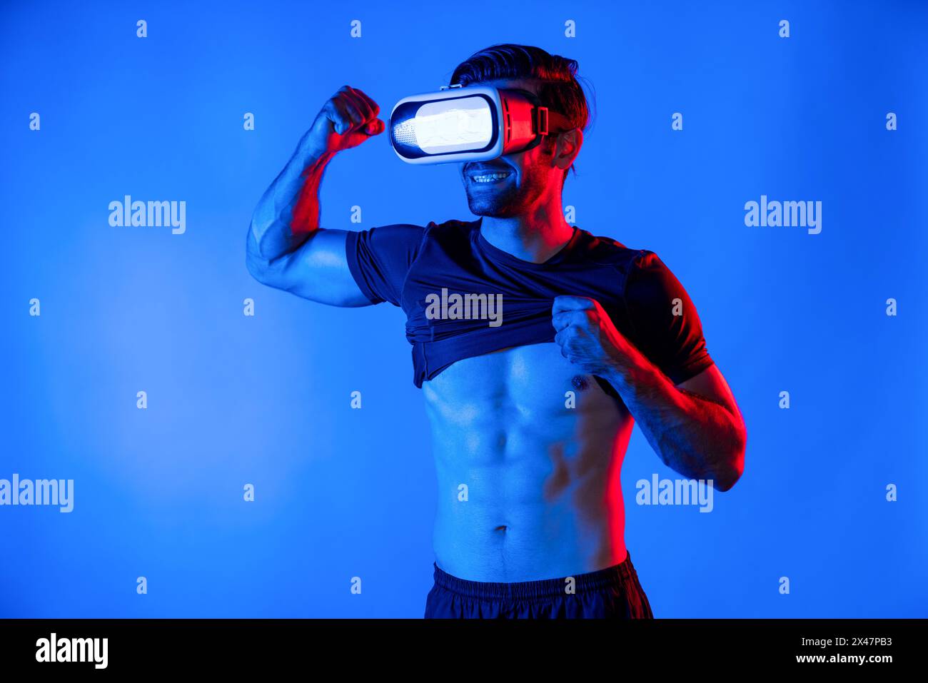 Happy man with VR goggle flexing muscle at neon light background ...