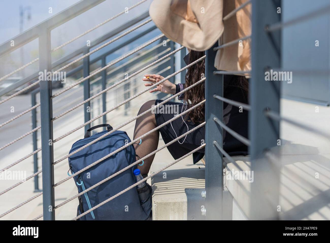 Unknown woman having a cigarette break. Female taking a sit on the stairs and resting with a ...