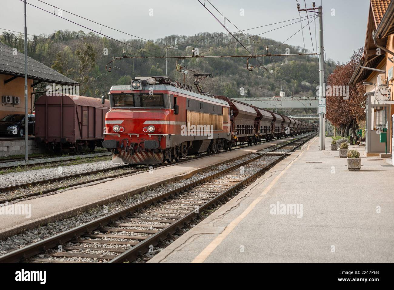 Freight train moving through the old station of Krsko. Red locomotive ...