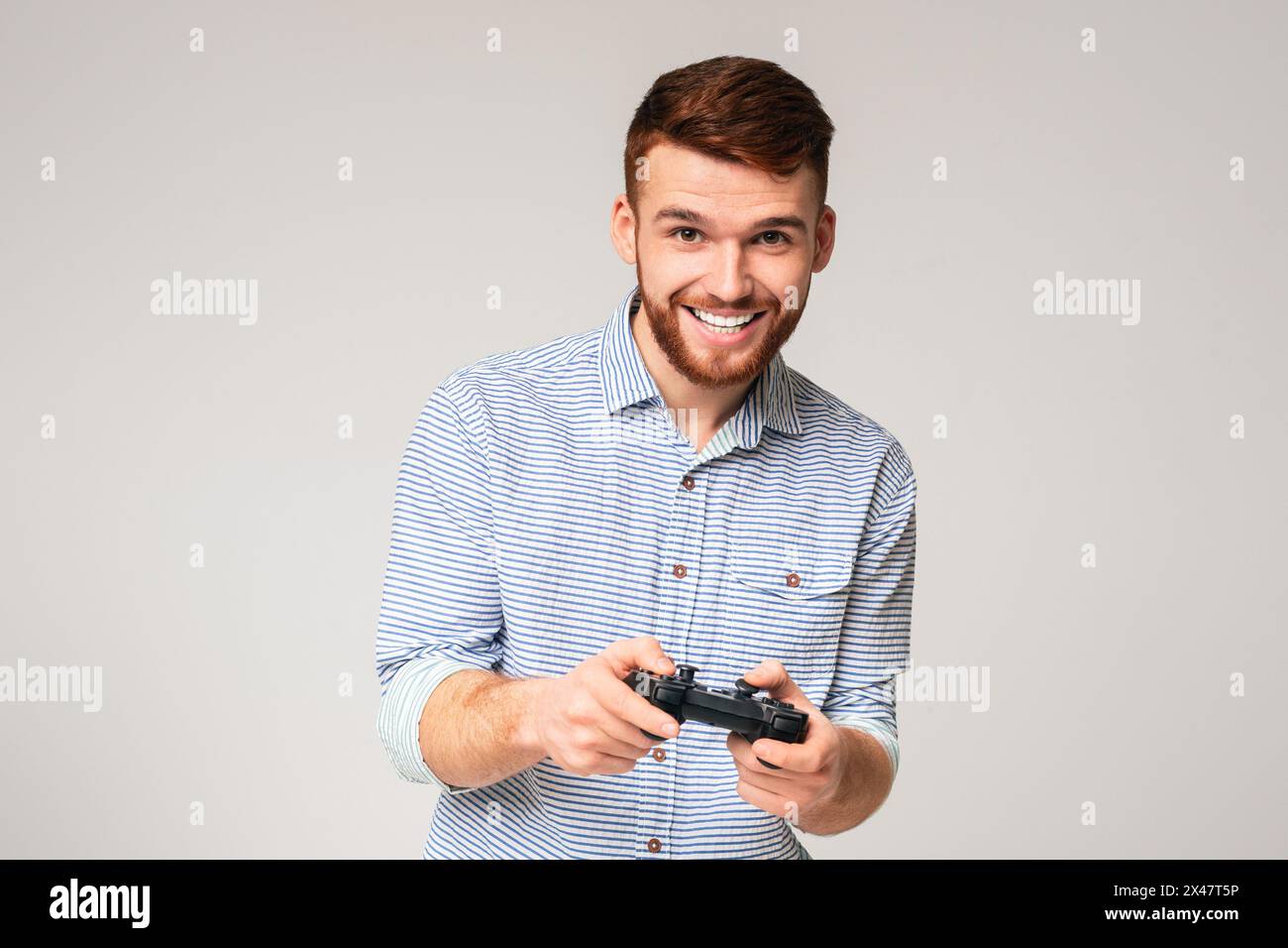 Excited millennial guy playing video games with jpystick Stock Photo ...