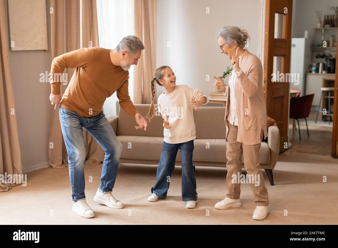 Joyful Grandparents Dancing With Young Granddaughter at Home Stock ...