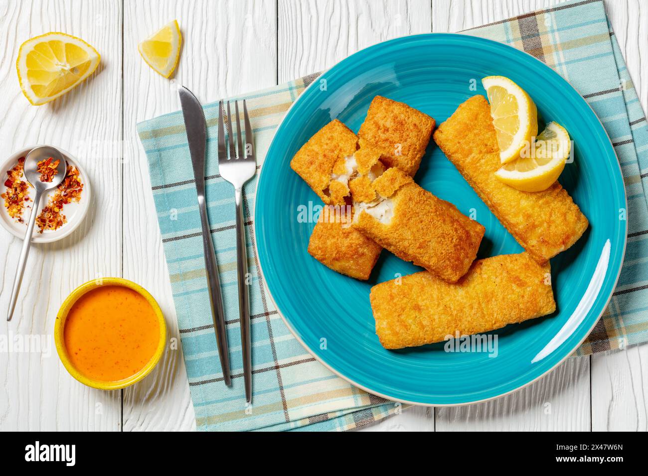 crispy fried battered alaskan pollock fillet on blue dish with lemon ...