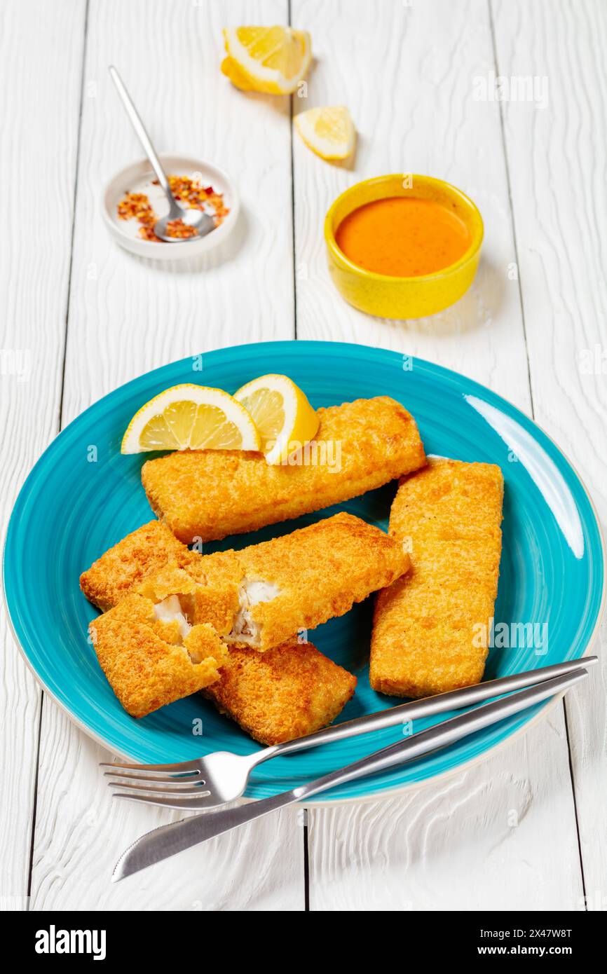 crispy baked battered alaskan pollock fillet on blue dish with lemon ...