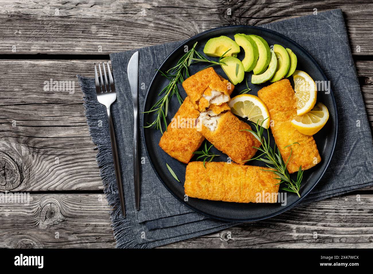 crispy baked battered alaskan pollock fillet on black dish with ...