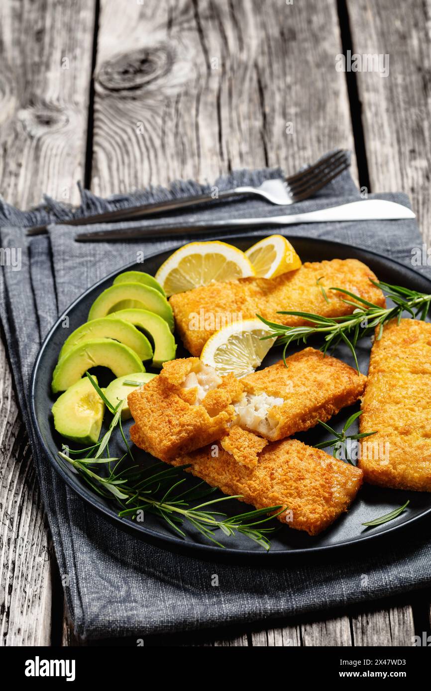 crispy baked battered alaskan pollock fillet on black dish with ...