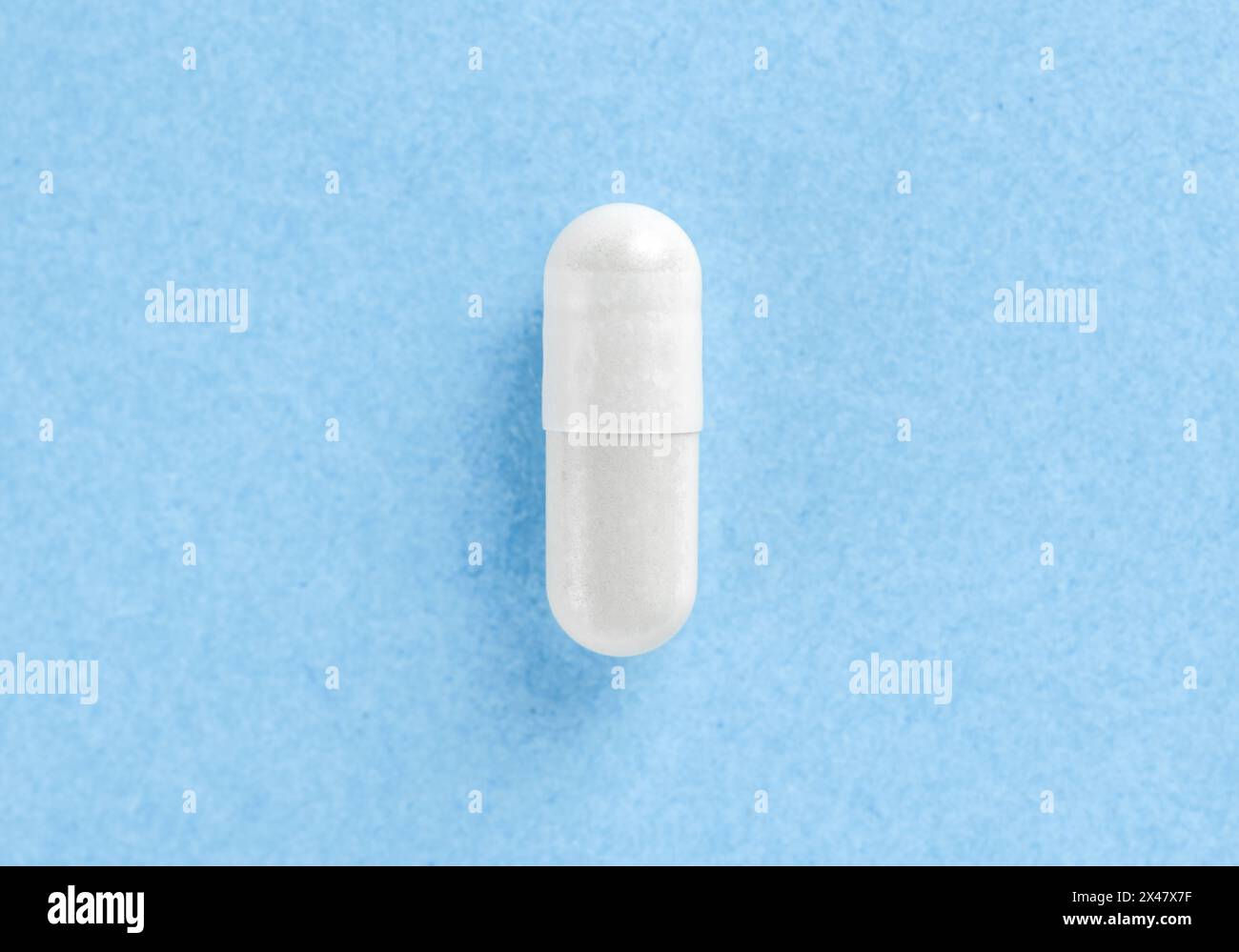 White two-piece hard starch capsule on blue background with copy space ...