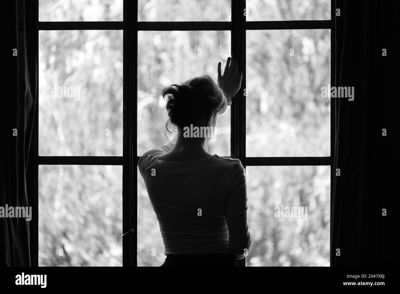 Young Woman looking out of a window in Monochrome Stock Photo - Alamy